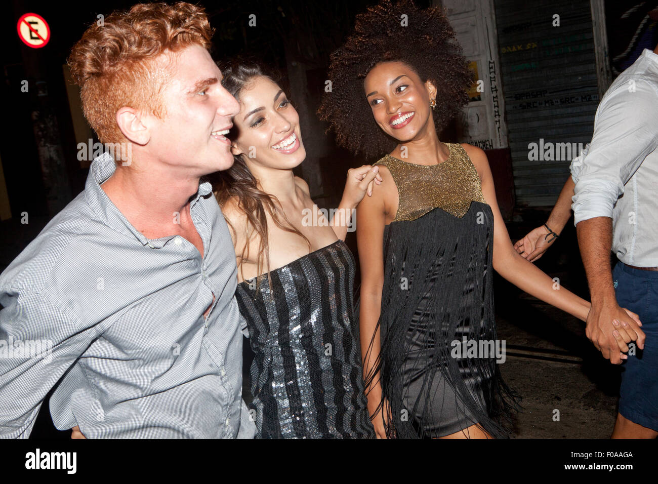 Four friends walking along street together at night Stock Photo - Alamy
