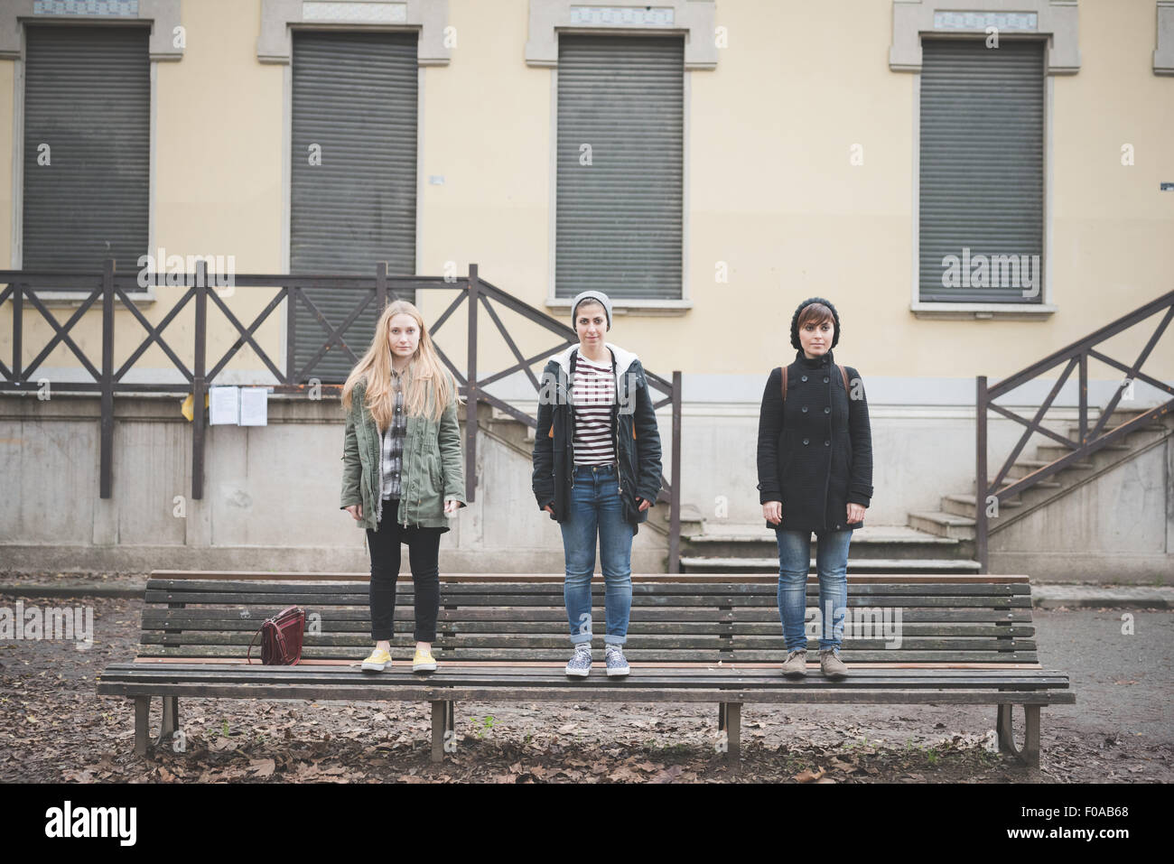 Three sisters standing on park bench Stock Photo - Alamy