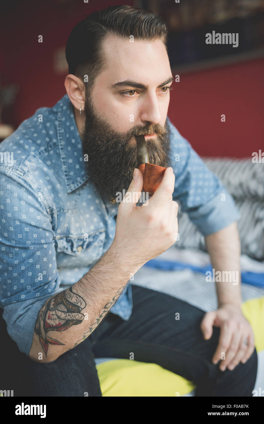 Young bearded man smoking pipe on bed Stock Photo - Alamy