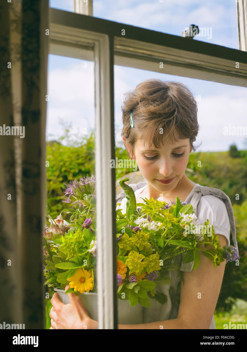 Young woman outside window with a bowl of wildflowers Stock Photo - Alamy