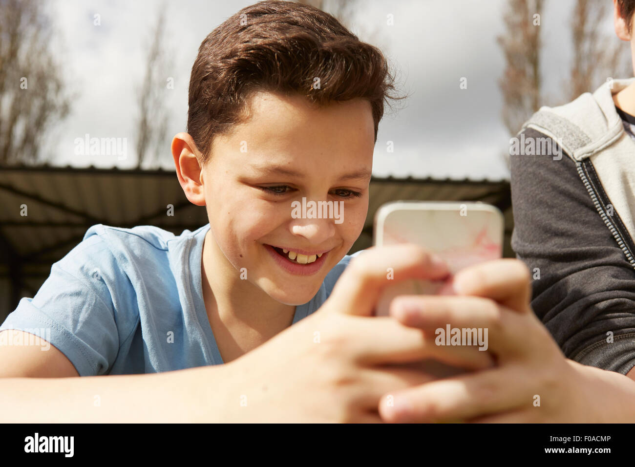 Smiling boy reading smartphone text message Stock Photo - Alamy
