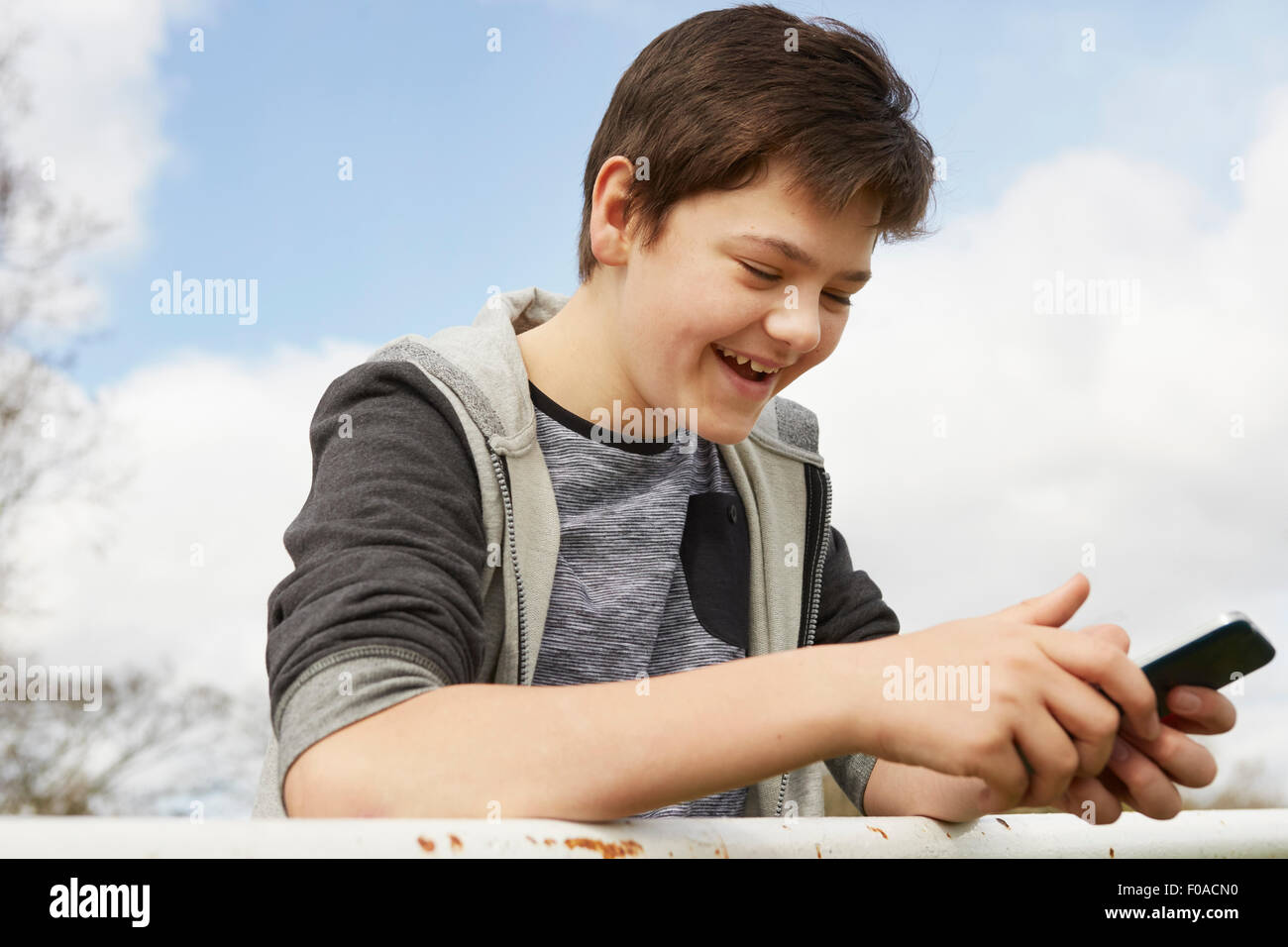 Smiling teenage boy reading smartphone text message Stock Photo - Alamy