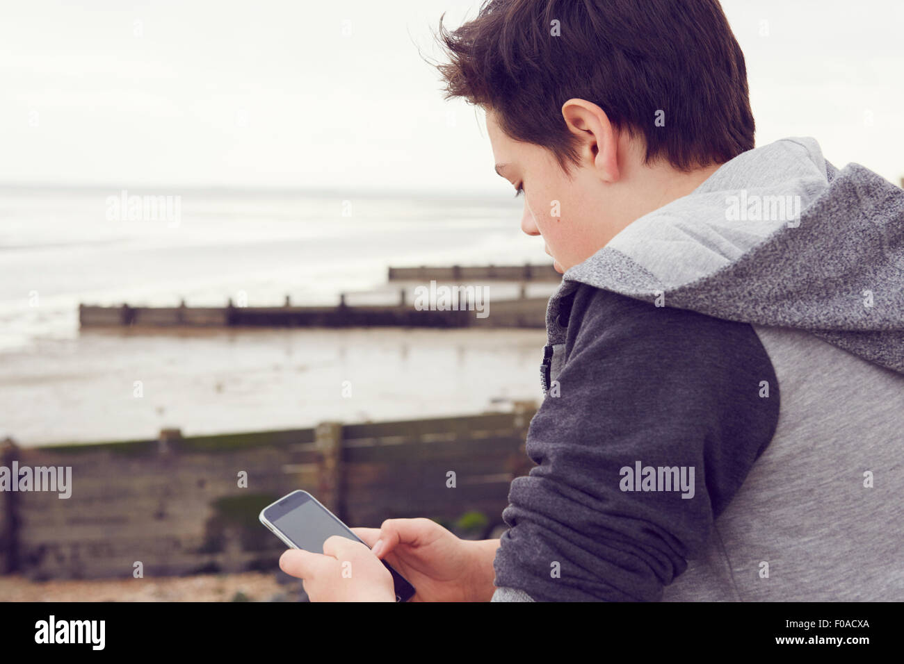 Teenage boy at seaside texting on smartphone, Southend on Sea, Essex ...