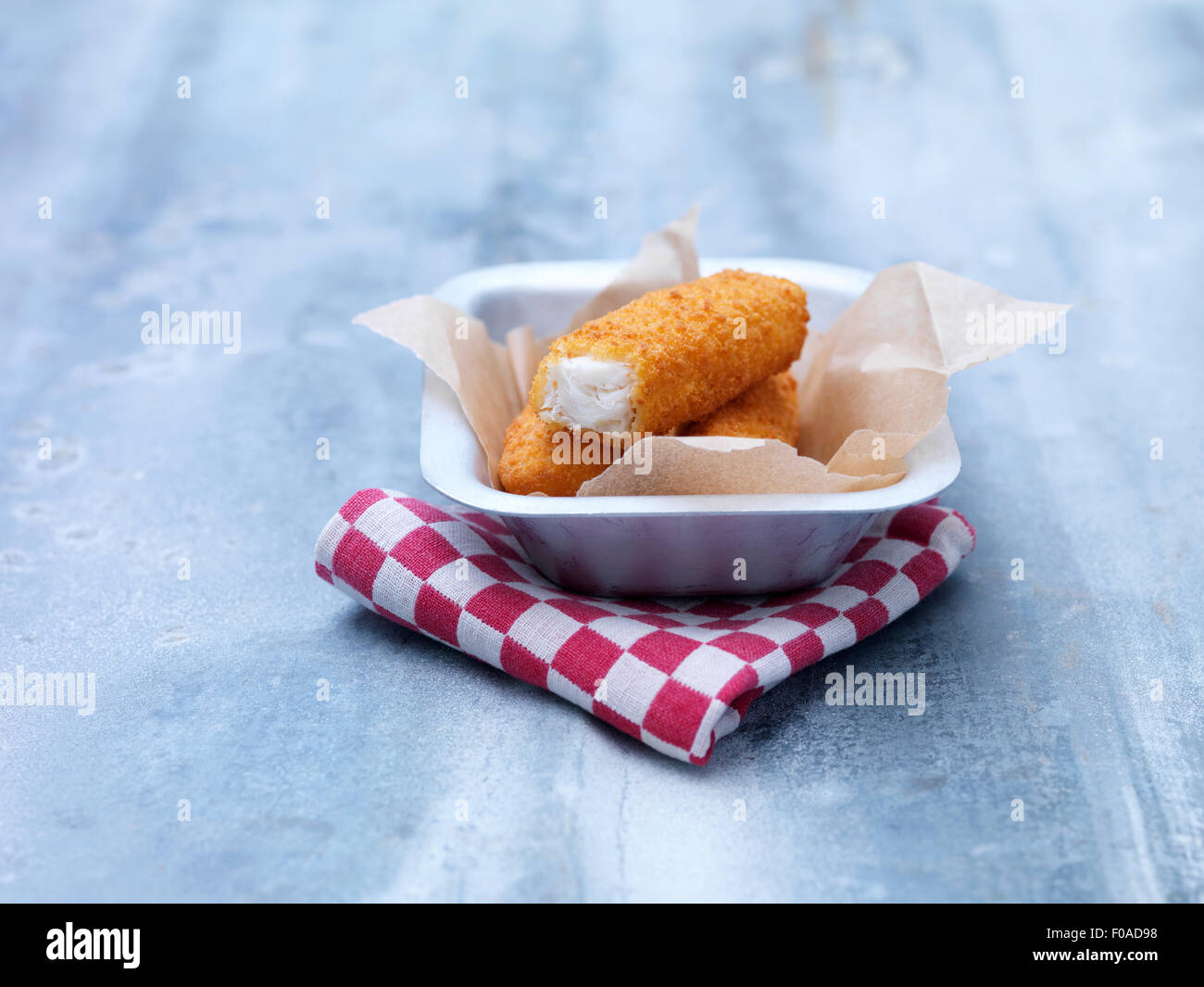 Fried chunky breaded cod fish fingers in baking tin on steel table ...