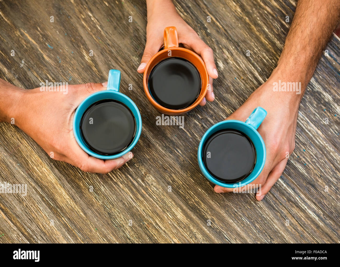 Hands holding cups of coffee over a table Stock Photo - Alamy