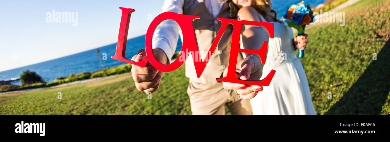 bride with groom holding bouquet and word love Stock Photo - Alamy