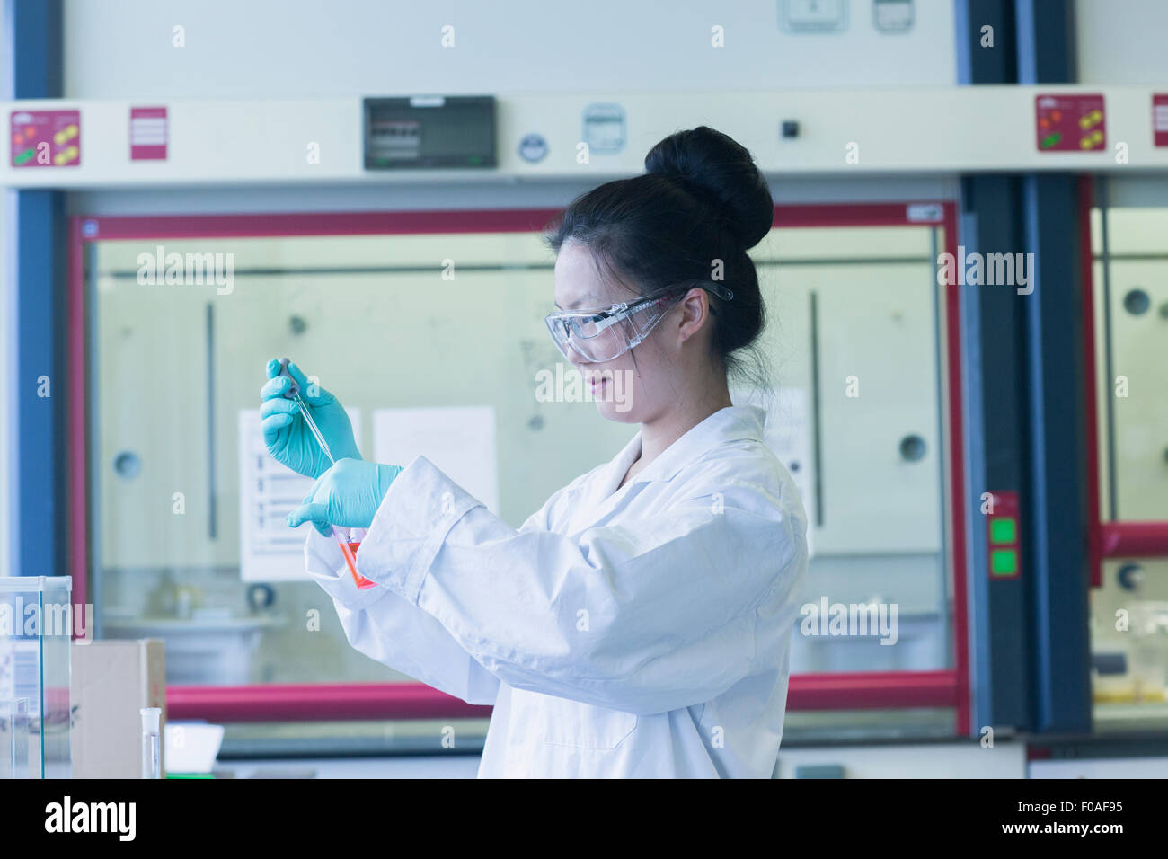 Female scientist in lab pipetting sample into lab beaker Stock Photo ...