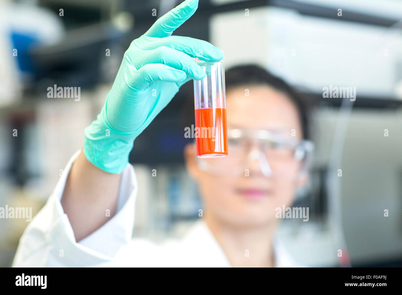 Young female lab technician holding up orange sample in lab Stock Photo ...