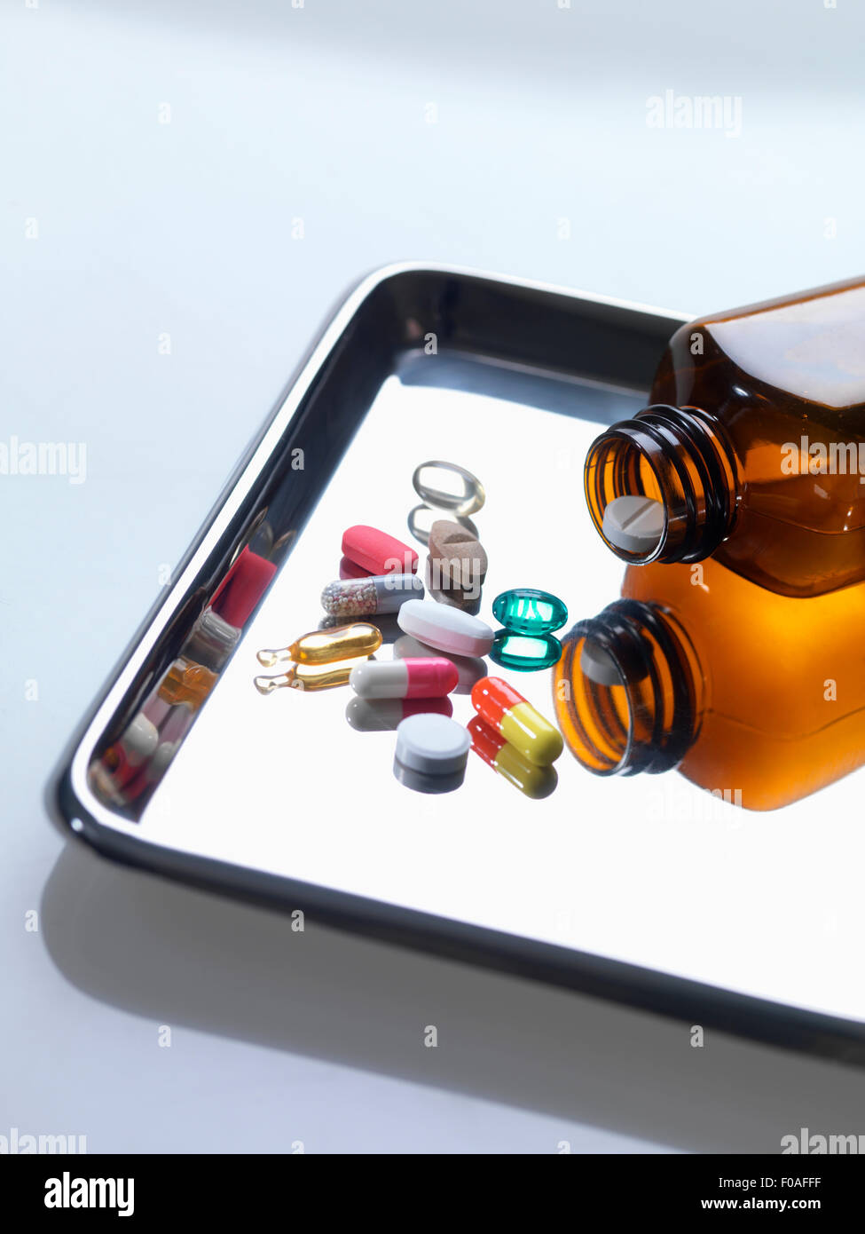 Variety of medical drugs pouring from pill bottle on surgical tray ...