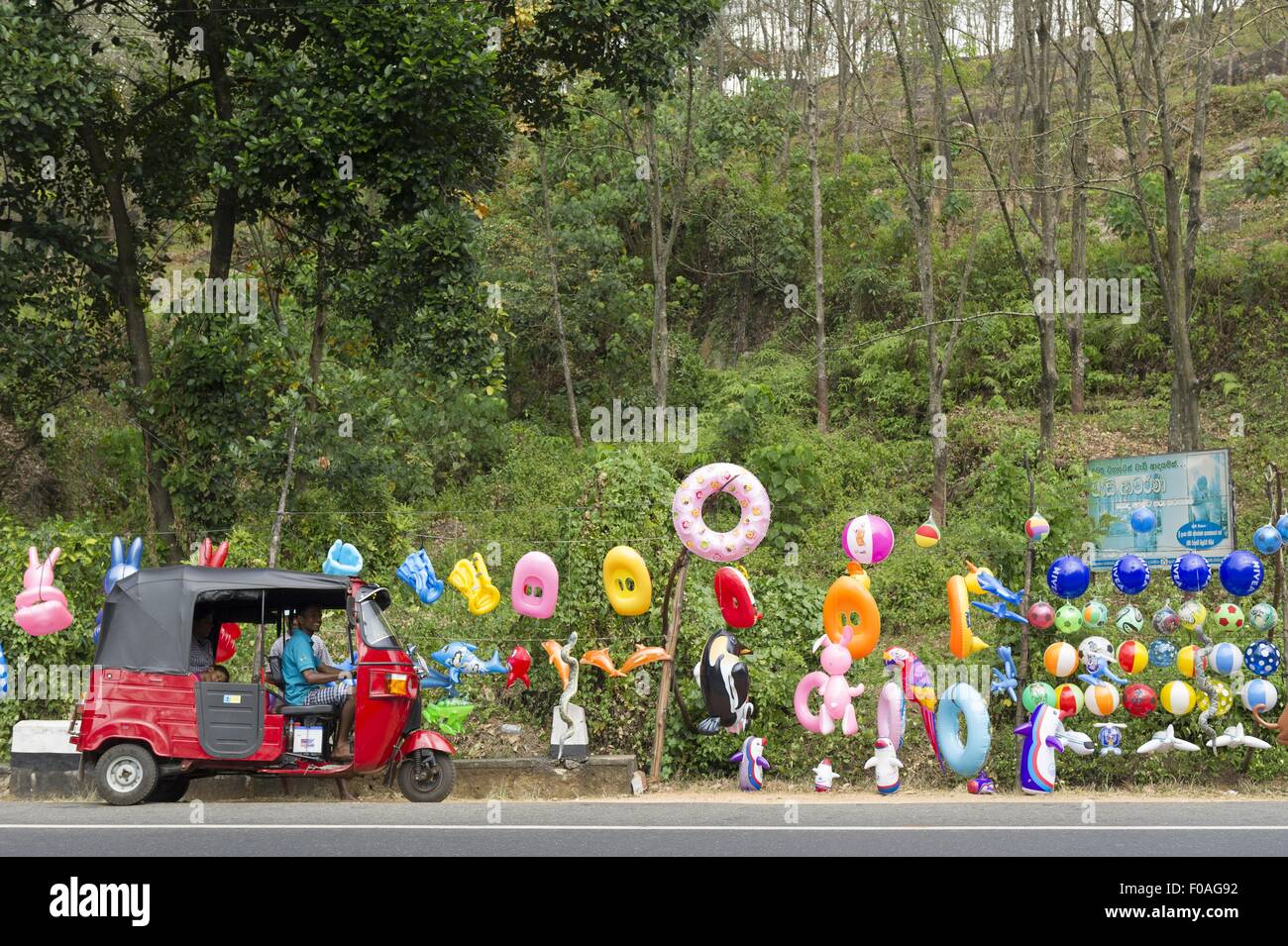Auto rickshaw in front of colourful floating tubes and toys on street ...