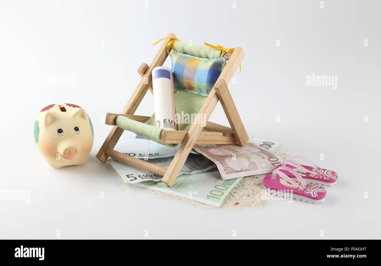 Rolled bill on deck chair, flip-flops, sand and piggy bank on white ...