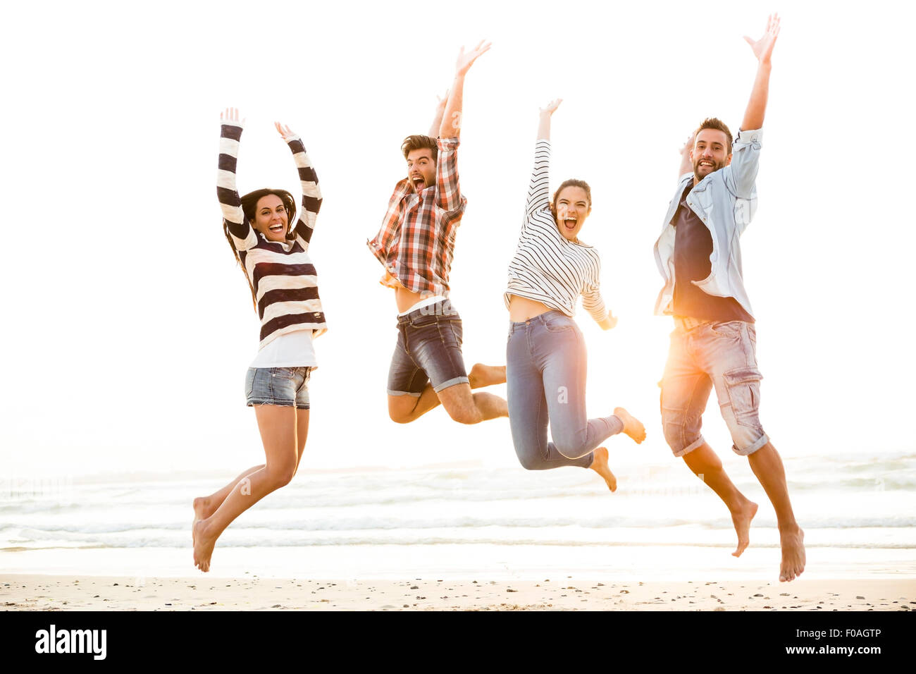 Group of friends making a jump together at the beach Stock Photo - Alamy