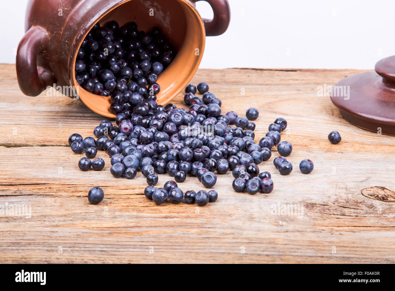 Strawberry, blueberry, or raspberry scattered from pot over wooden ...
