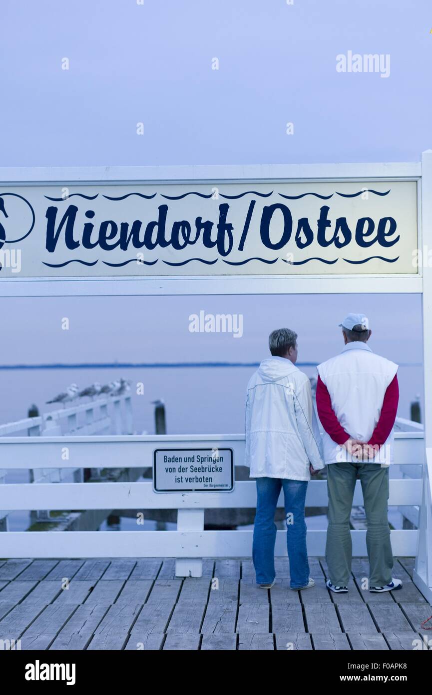 Rear view of two people standing on Niendorf harbour, Schleswig ...
