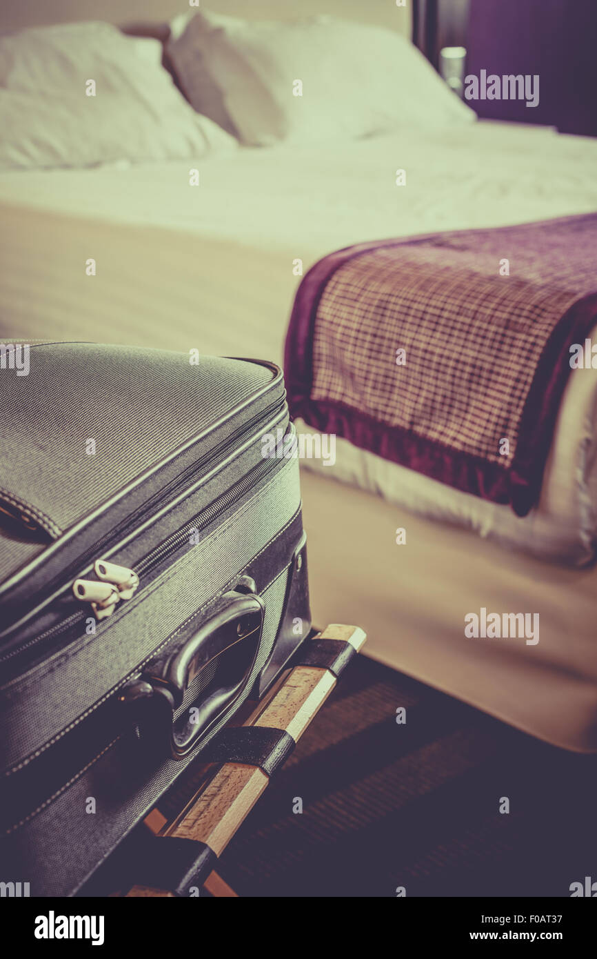 Hotel room with a suitcase on the luggage place and the bed. Filtered ...