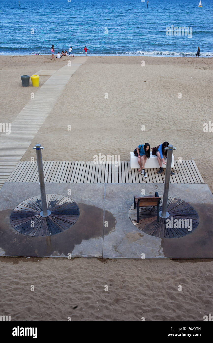 Beach showers and wooden plank path leading to the sea in Barceloneta ...