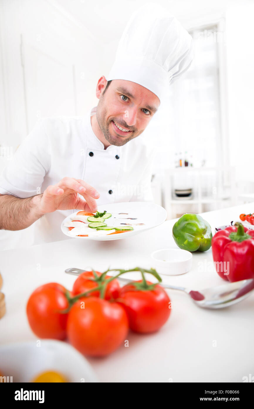 View of a Young attractive professional chef cooking in his kitchen ...