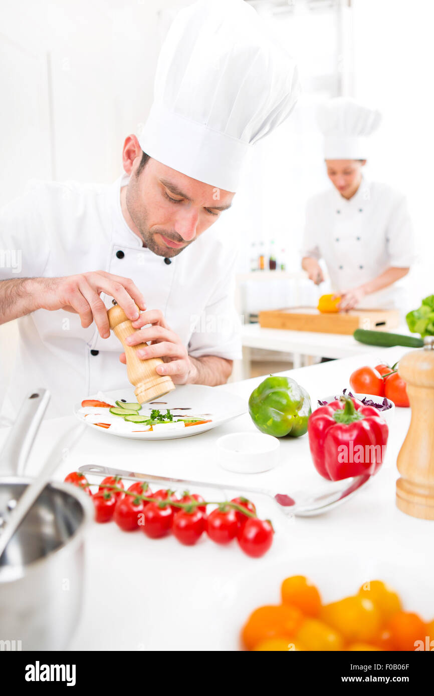 View of a Young attractive professional chef cooking in his kitchen ...