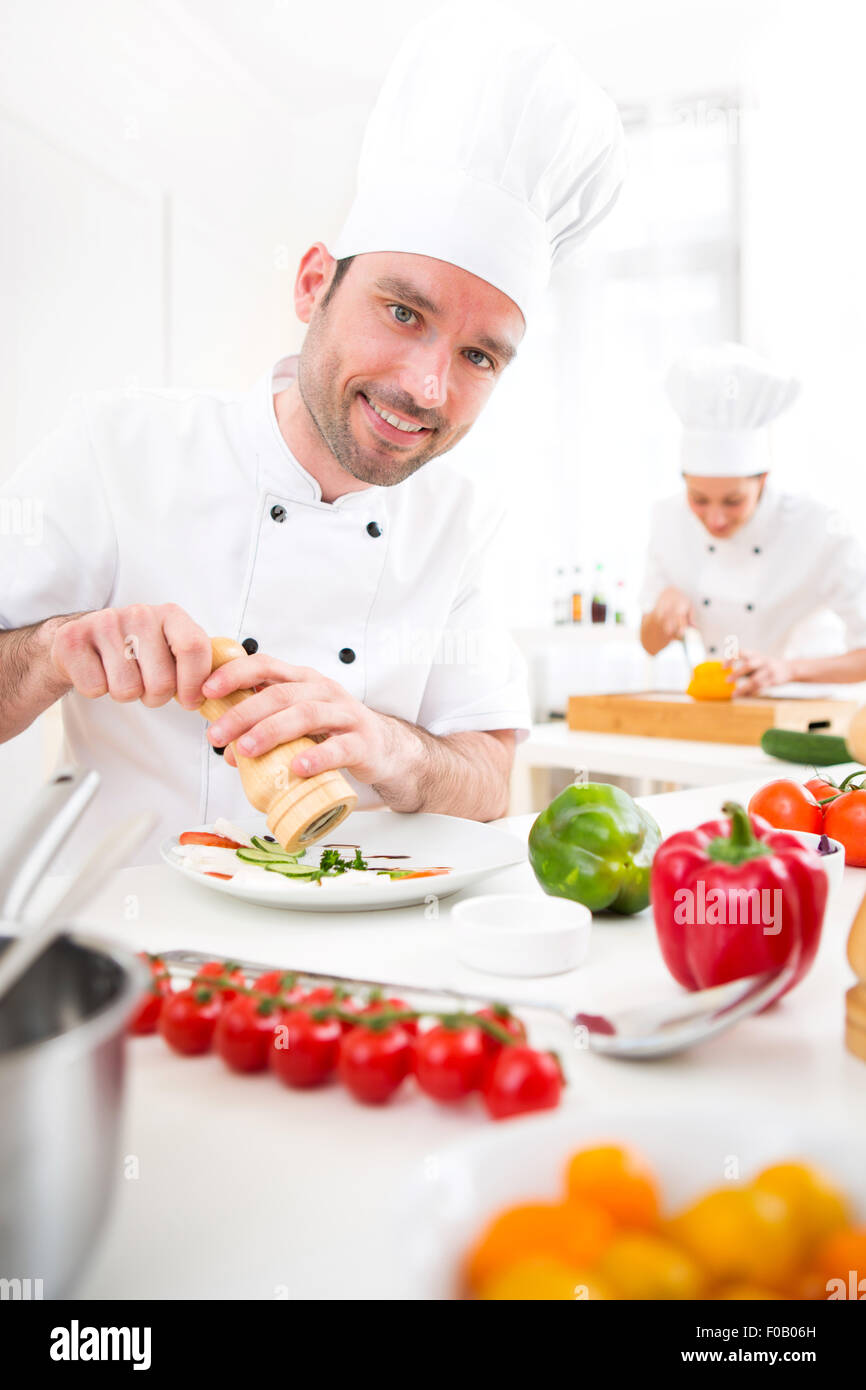 View of a Young attractive professional chef cooking in his kitchen ...