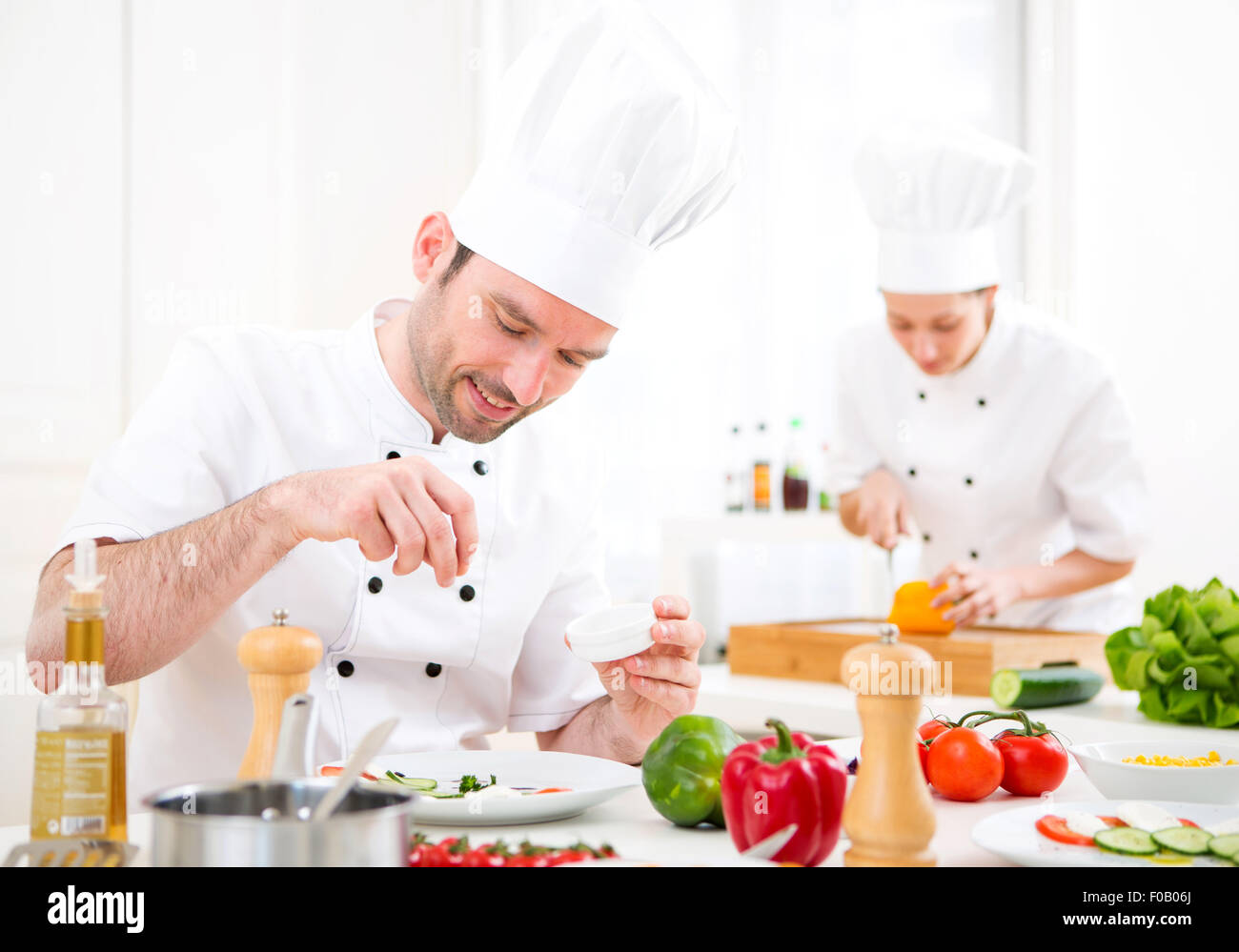 View of a Young attractive professional chef cooking in his kitchen ...