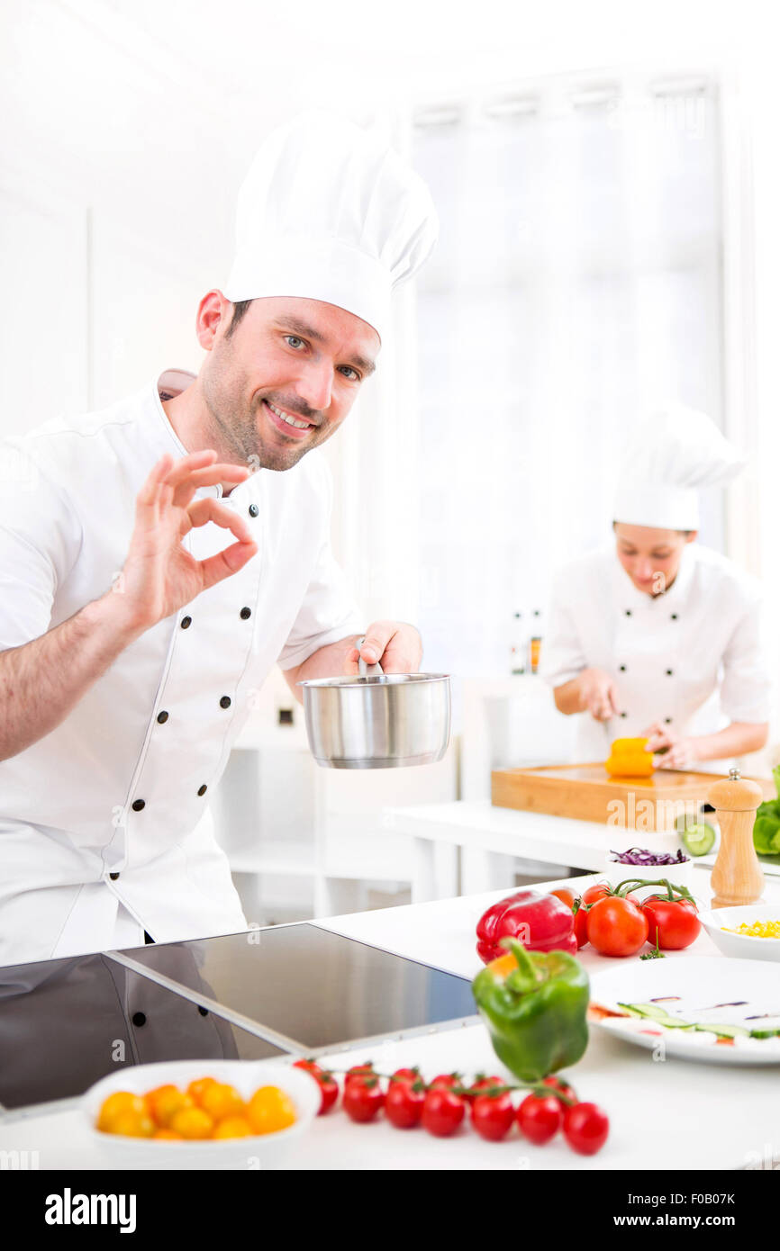 View of a Young attractive professional chef cooking in his kitchen ...