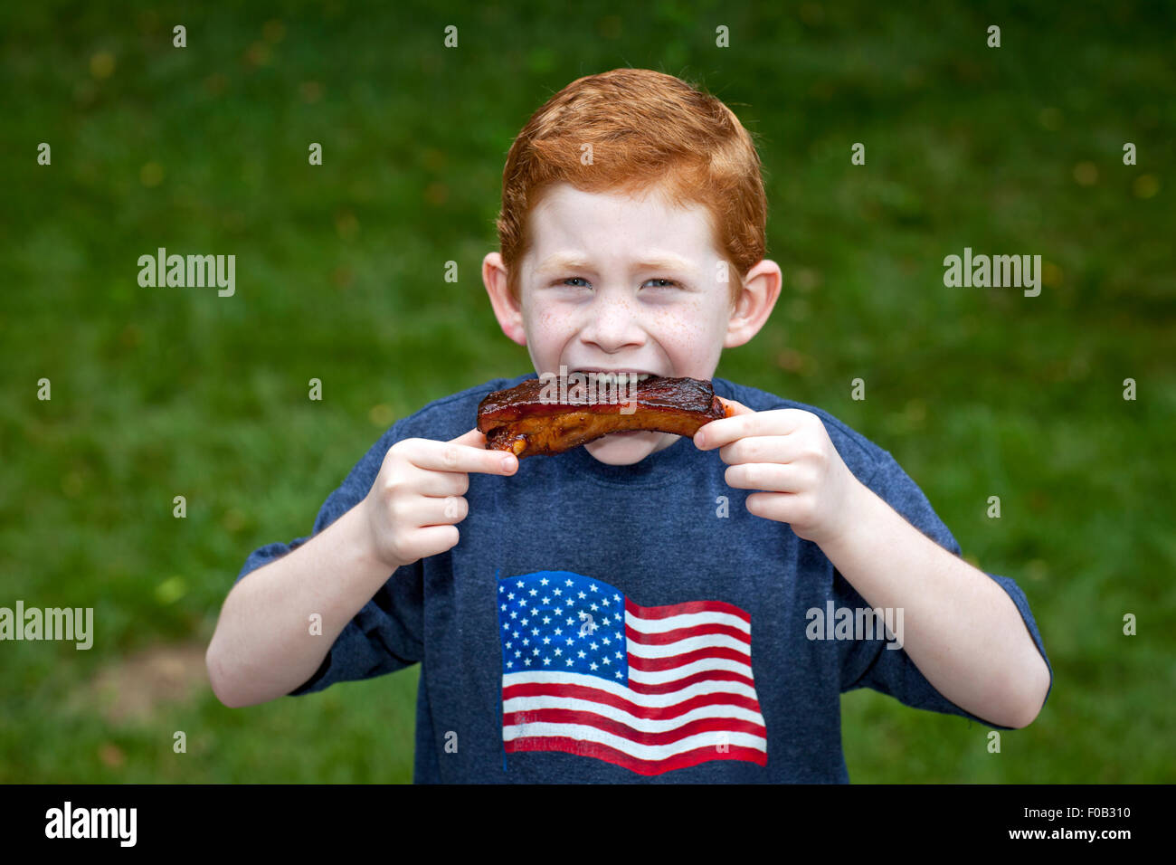 Boy eating a BBQ rib outside getting messy Stock Photo - Alamy