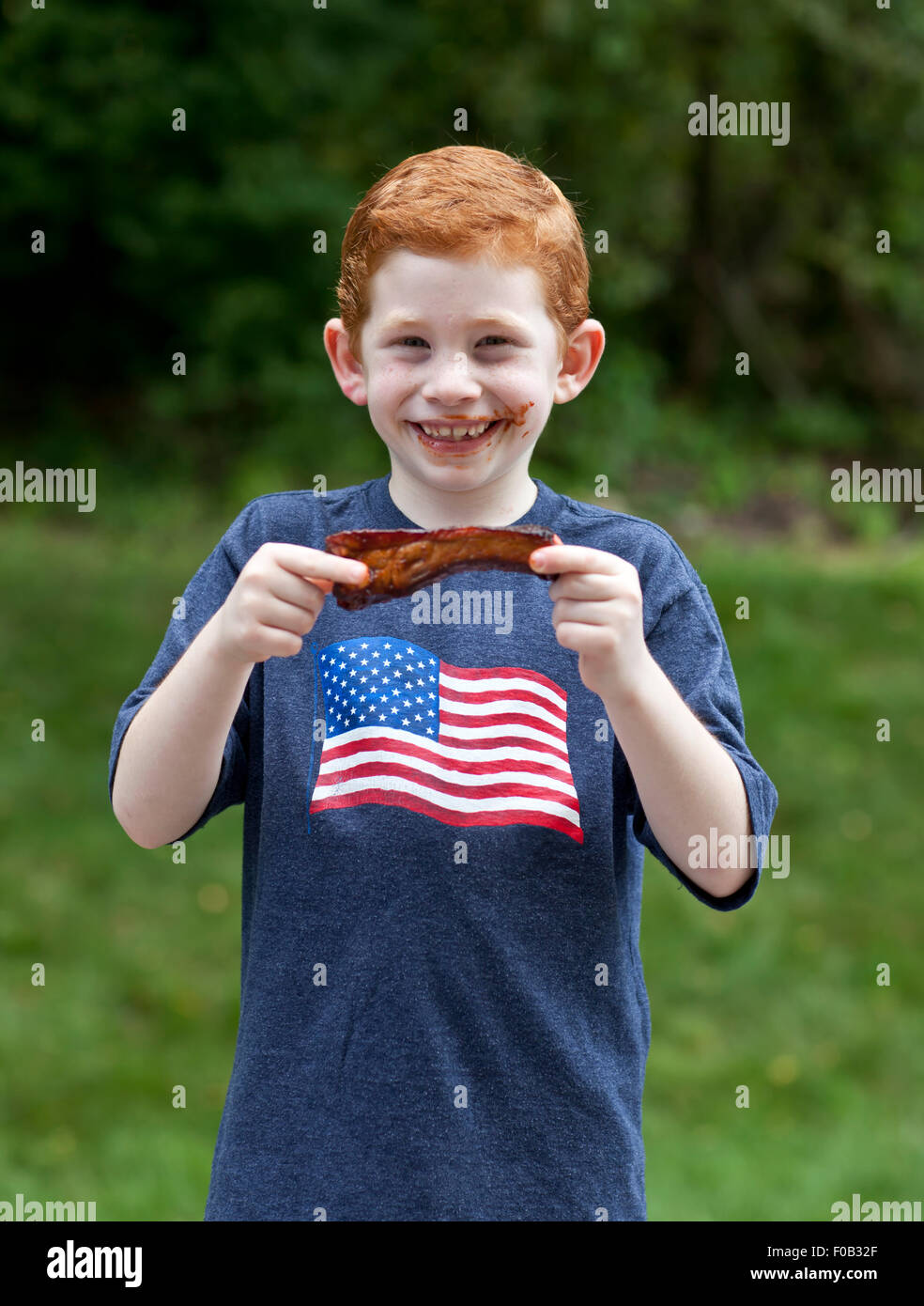 Boy eating a BBQ rib outside getting messy Stock Photo - Alamy