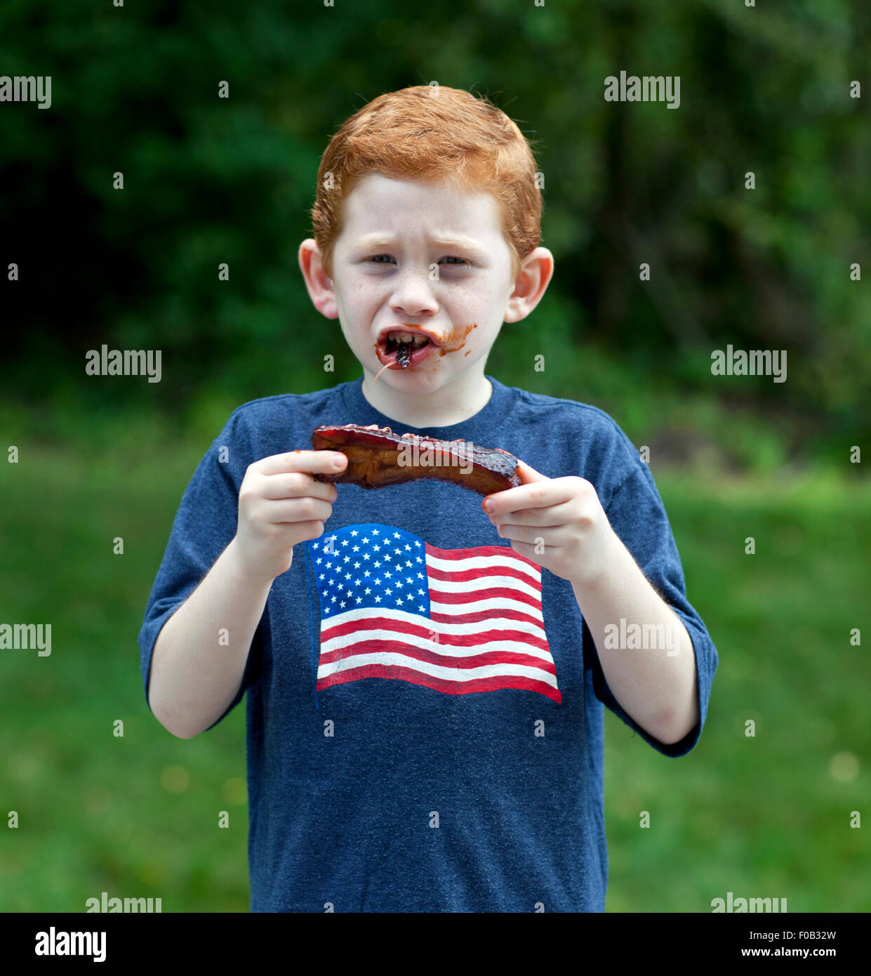 Boy eating a BBQ rib outside getting messy Stock Photo - Alamy