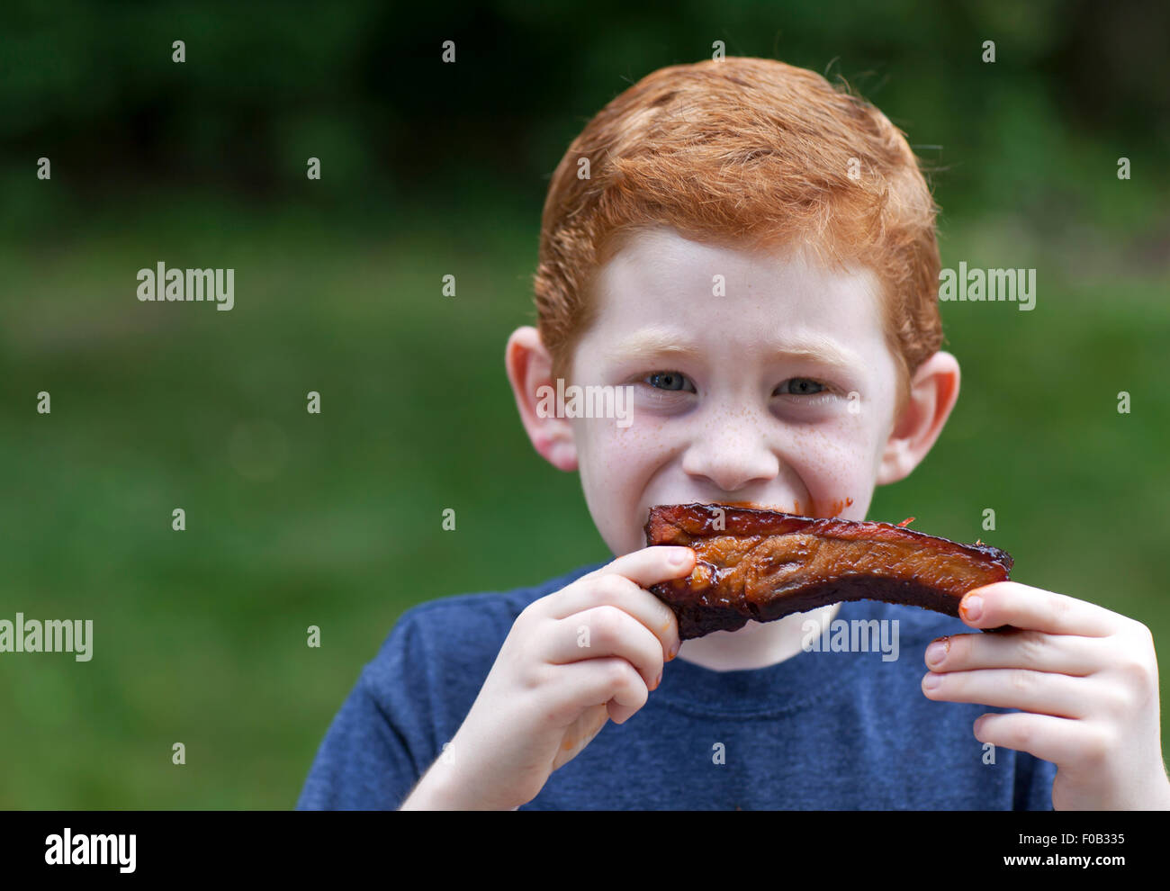 Boy eating a BBQ rib outside getting messy Stock Photo - Alamy