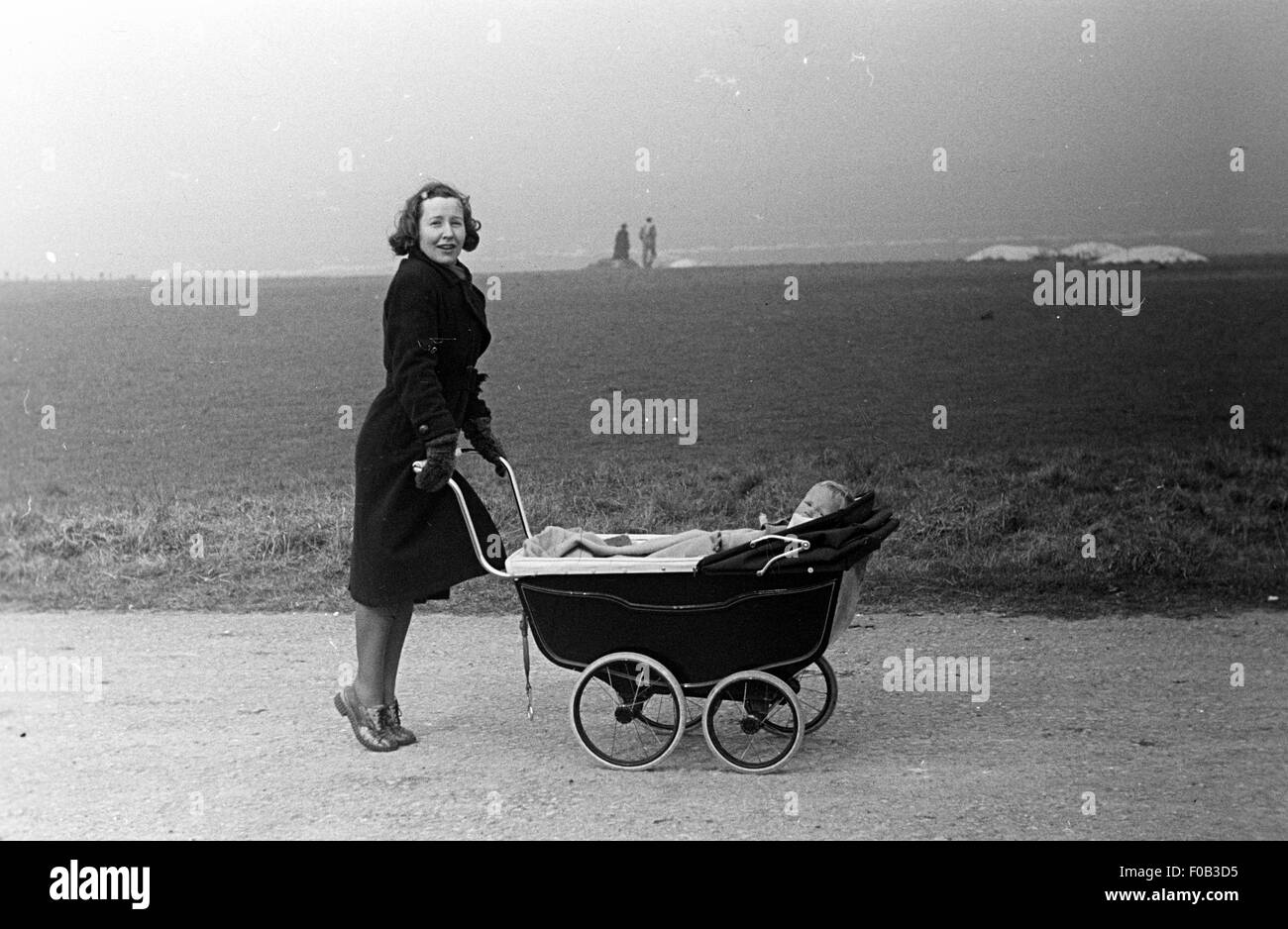 A woman pushing a baby in a pram Stock Photo - Alamy