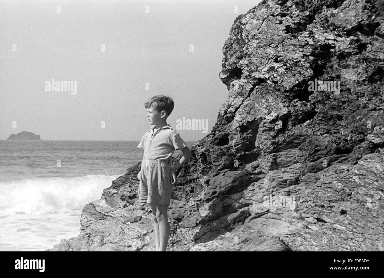 A boy standing on rocks at a beach Stock Photo - Alamy