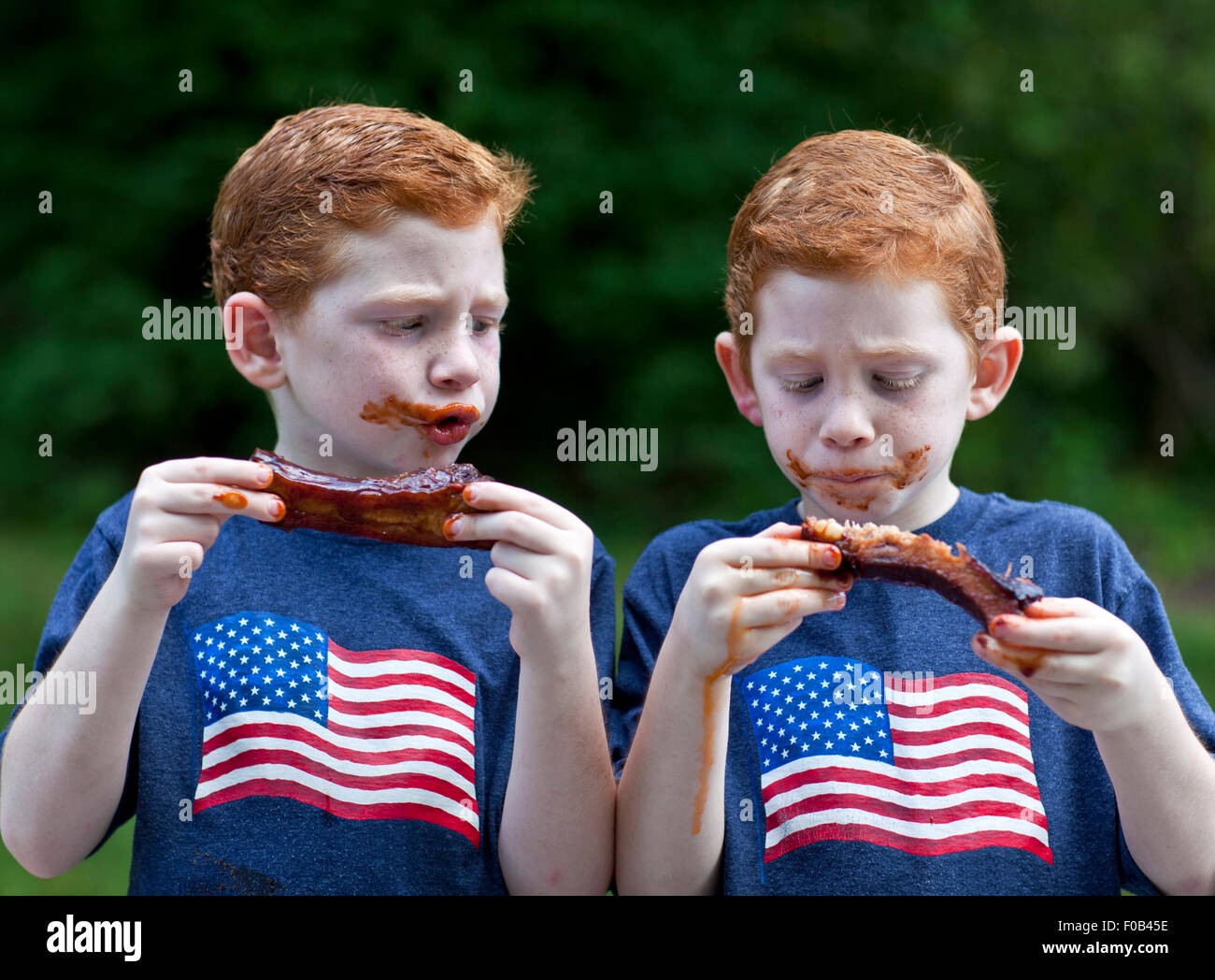 Boys eating a BBQ rib outside getting messy Stock Photo - Alamy