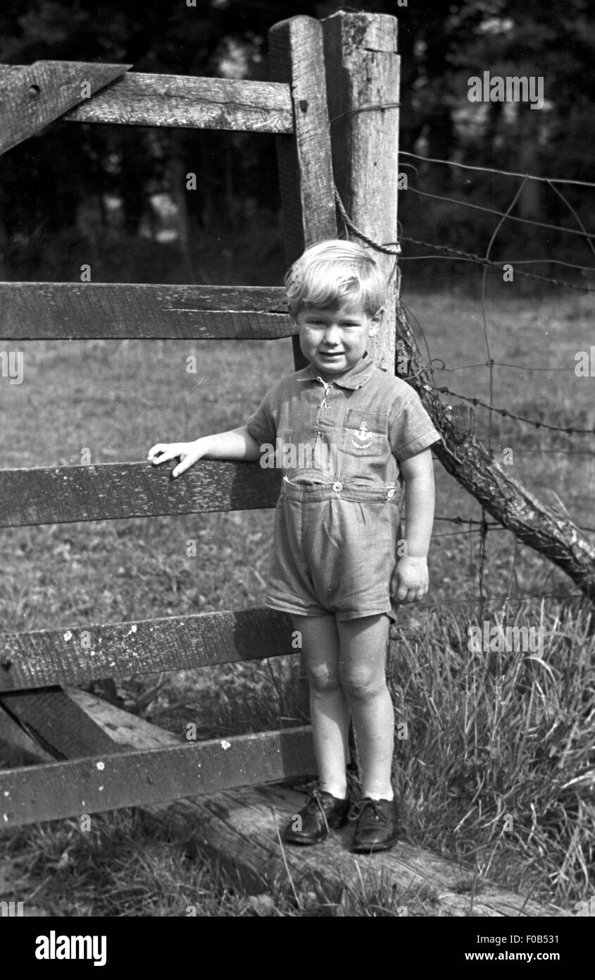 A young boy standing next to a gate Stock Photo - Alamy