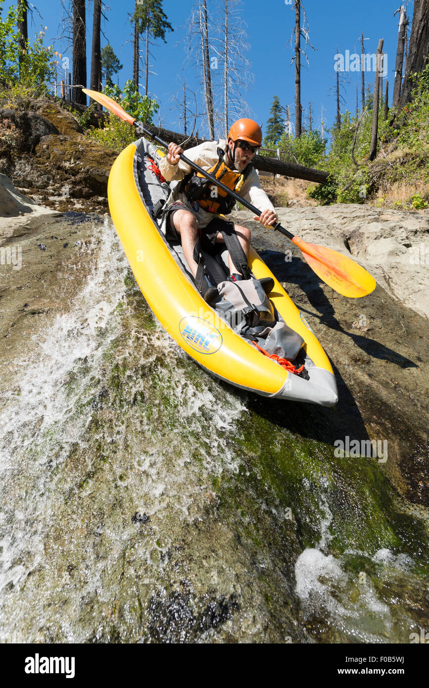 Paddling down a shallow slide on a stream in Oregon's Cascade Range ...