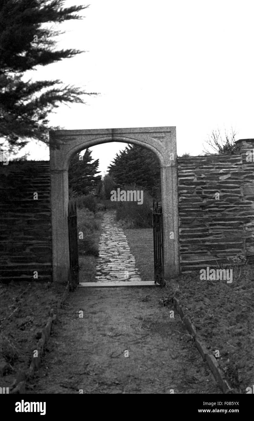 A stone arch with gates leading into a stone walled garden Stock Photo ...