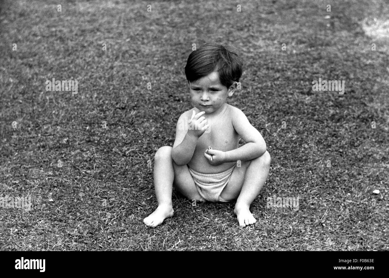 Little boy sitting on the grass in a nappy Stock Photo - Alamy
