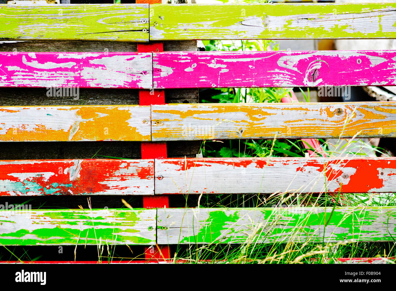 multicolored wooden fence painted and with grass Stock Photo - Alamy