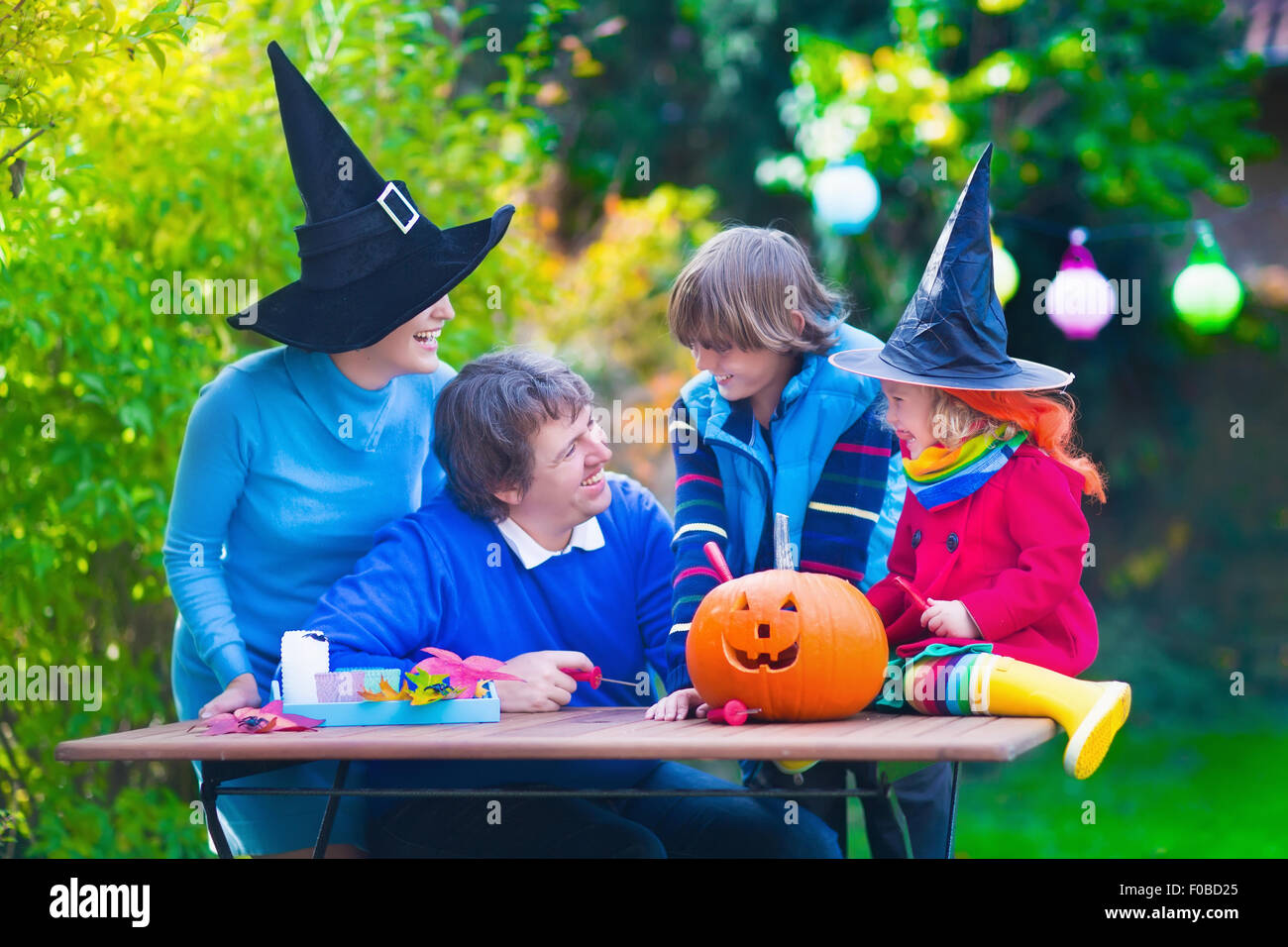 Family carving pumpkin at Halloween. Dressed up child trick or treating ...