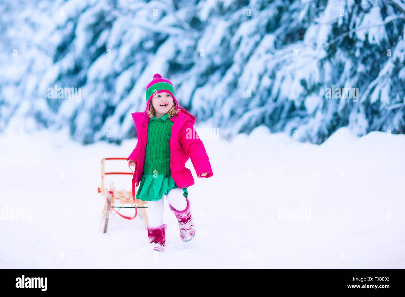 Little girl enjoying a sleigh ride. Child sledding. Toddler kid riding ...