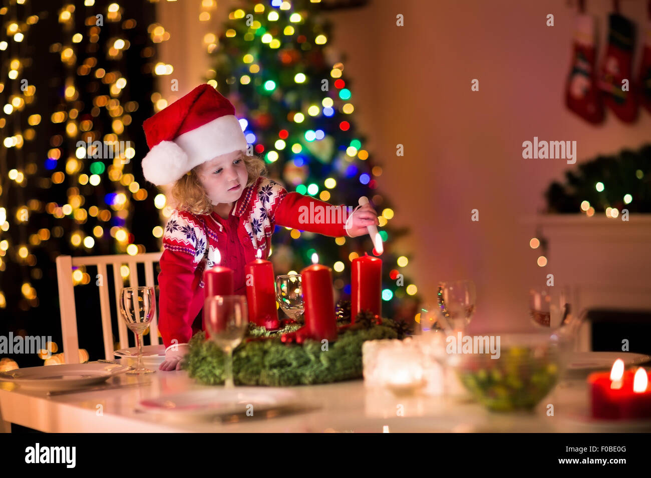 Christmas dinner at home. Child lighting a candle on advent wreath on ...