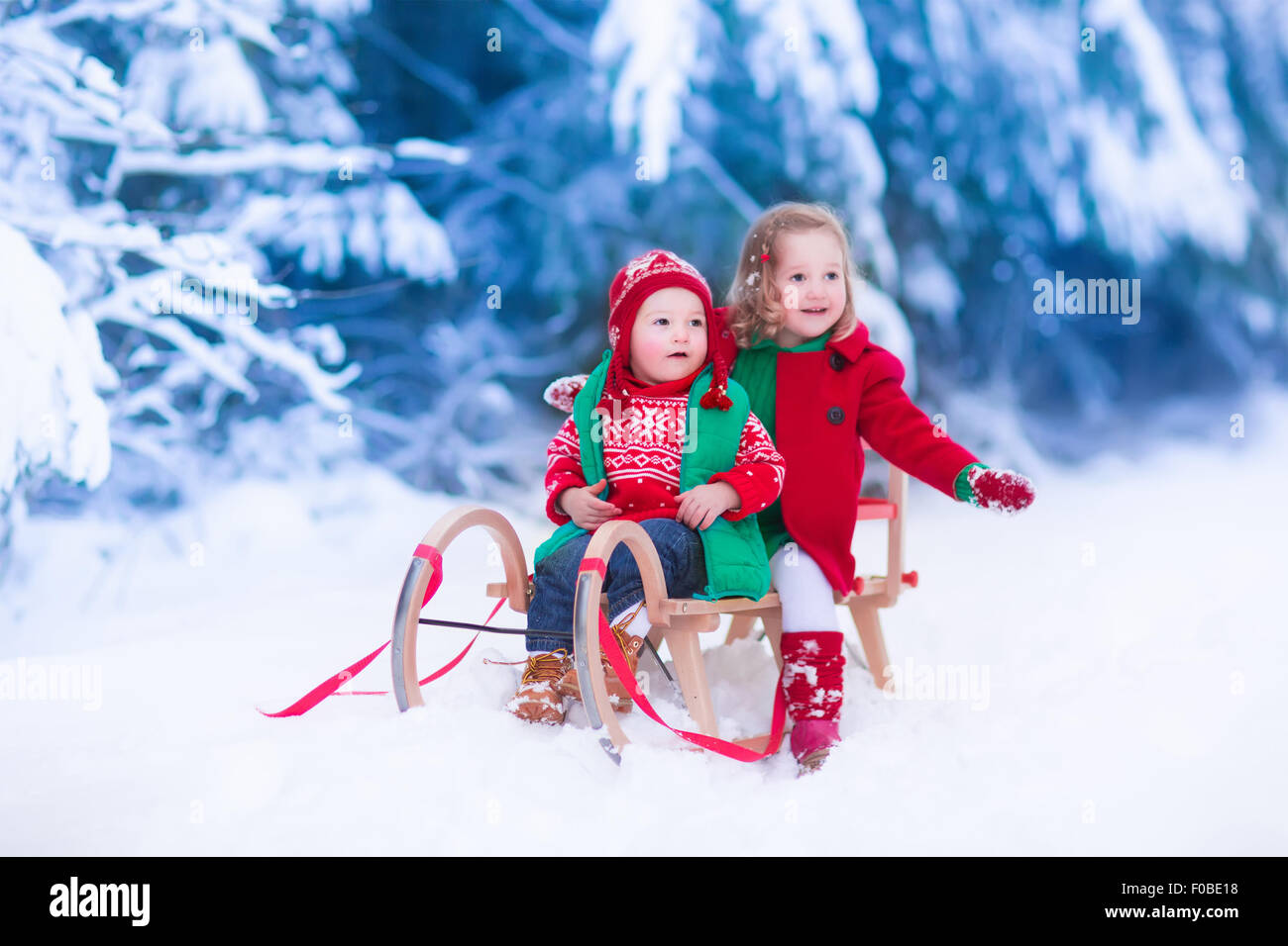 Little girl and baby boy enjoying a sleigh ride. Child sledding ...