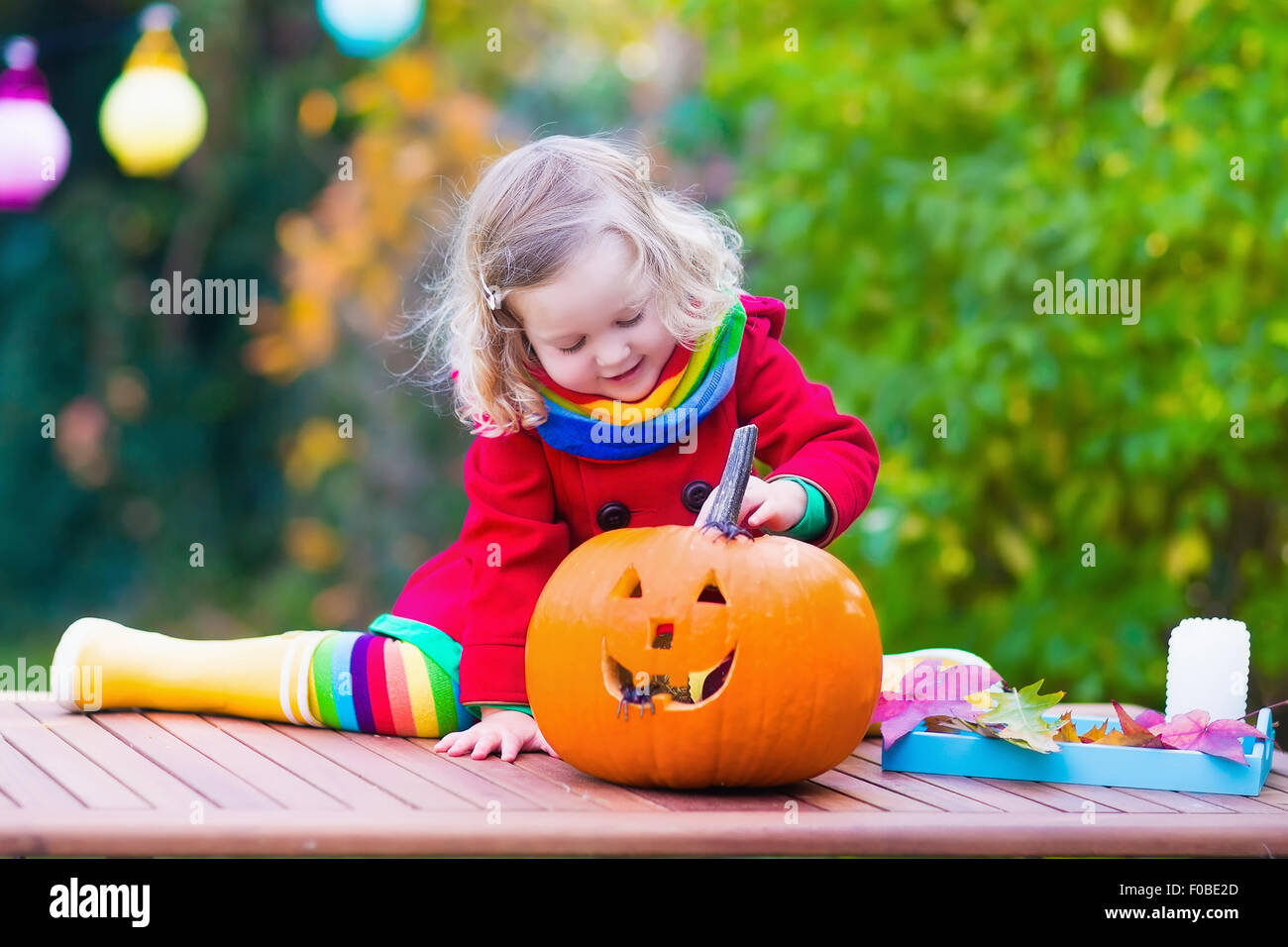 Little girl carving pumpkin at Halloween. Dressed up child trick or ...
