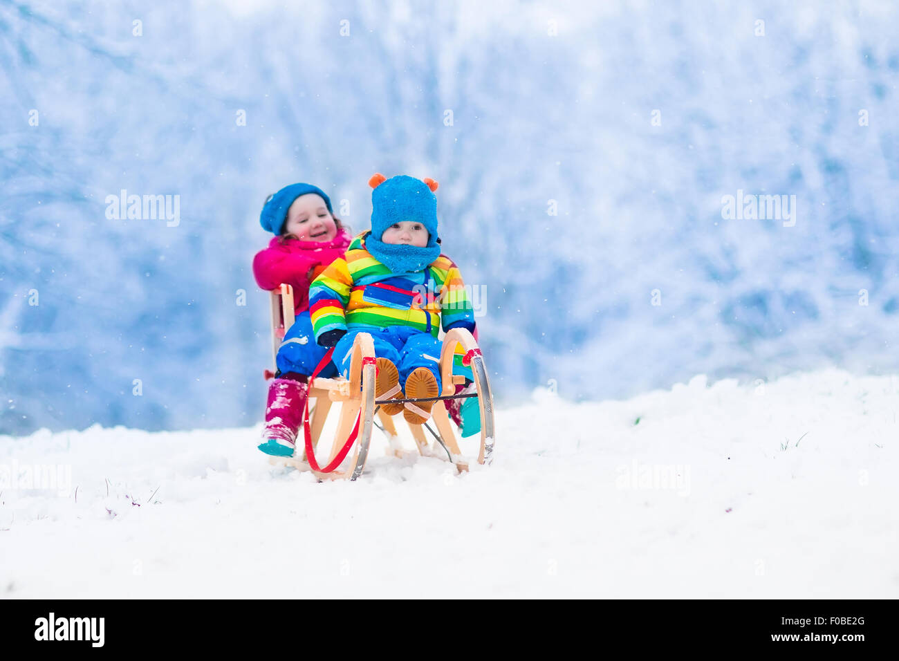 Little girl and baby boy enjoying a sleigh ride. Child sledding ...