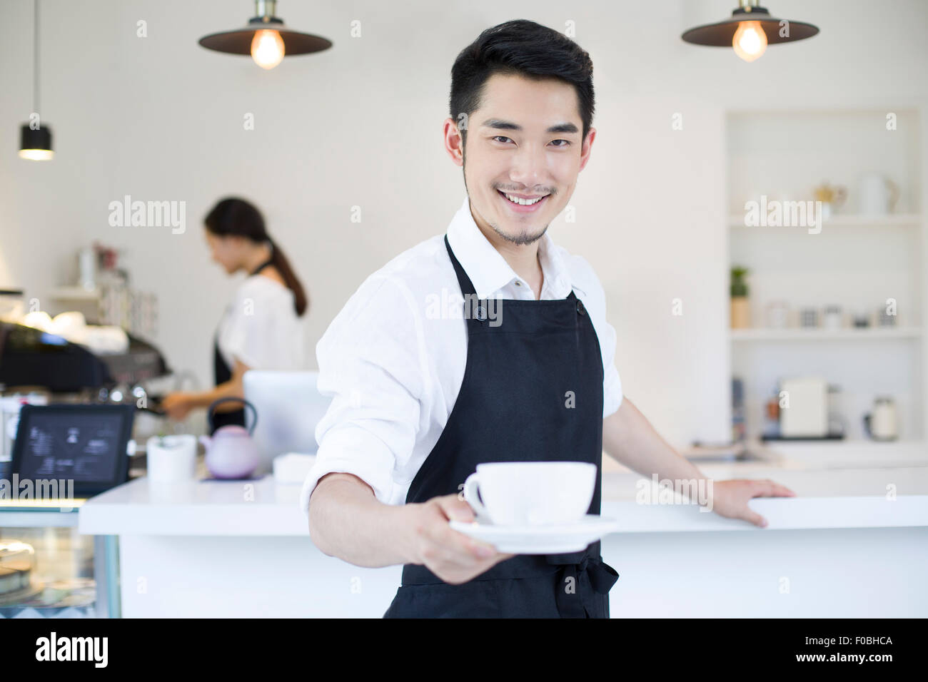 Coffee shop owner holding a cup of coffee Stock Photo - Alamy