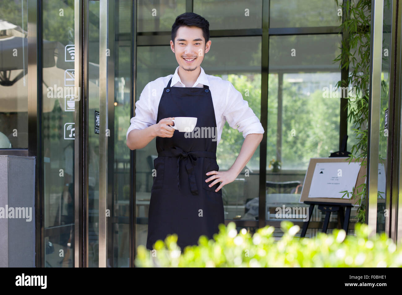 Shopkeeper standing in doorway of coffee shop Stock Photo - Alamy