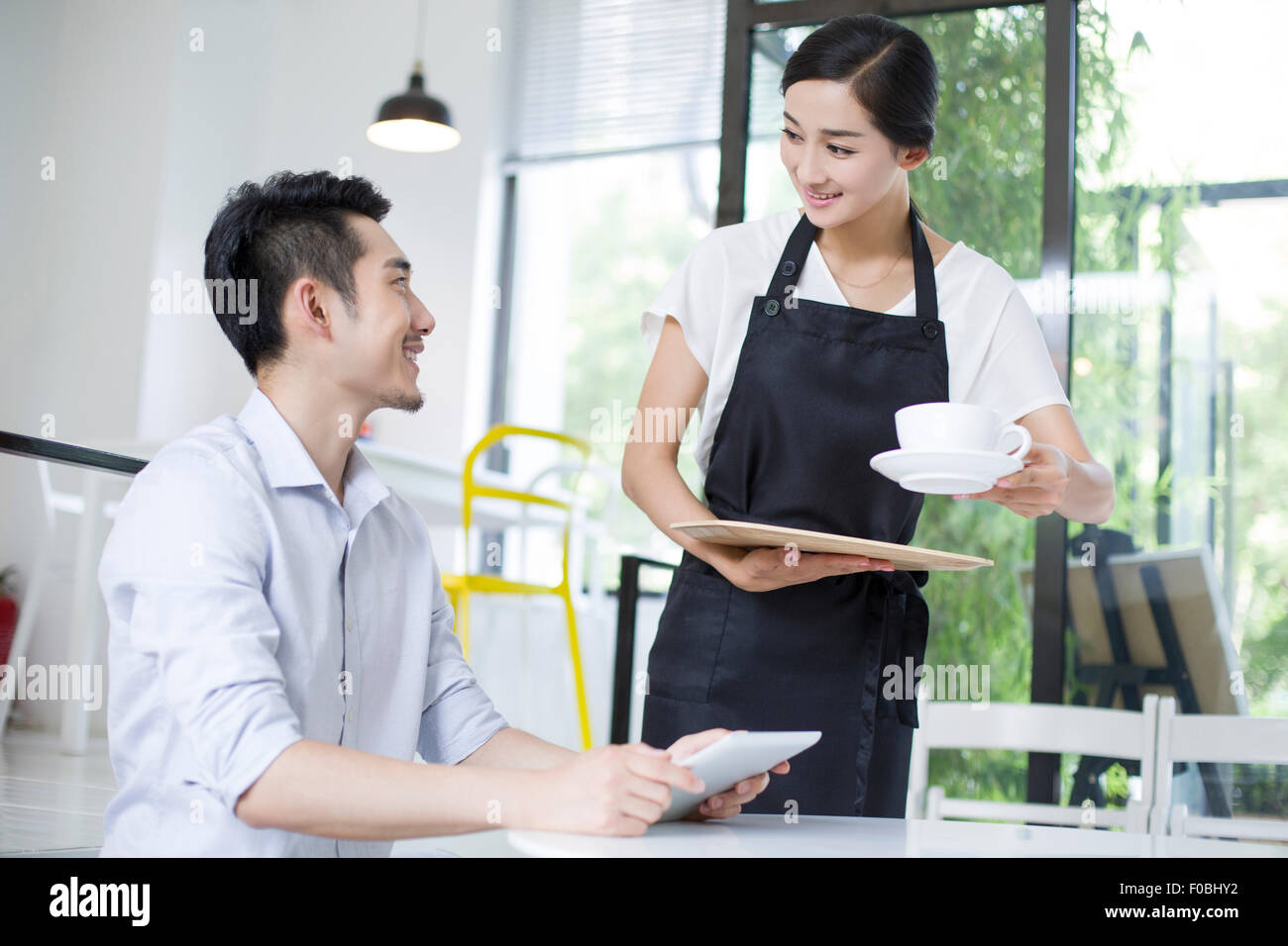 Waitress serving young man a cup of coffee Stock Photo - Alamy