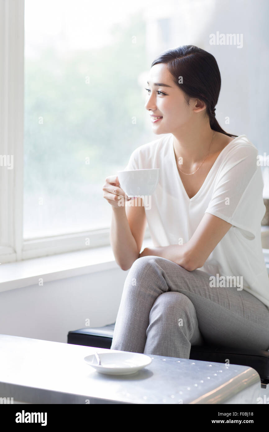 Happy young woman drinking coffee in coffee shop Stock Photo - Alamy