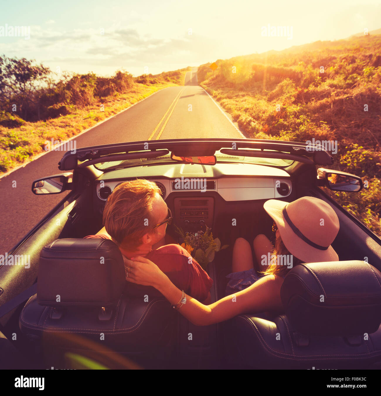 Happy Young Couple Driving Along Country Road in Convertable at Sunset ...