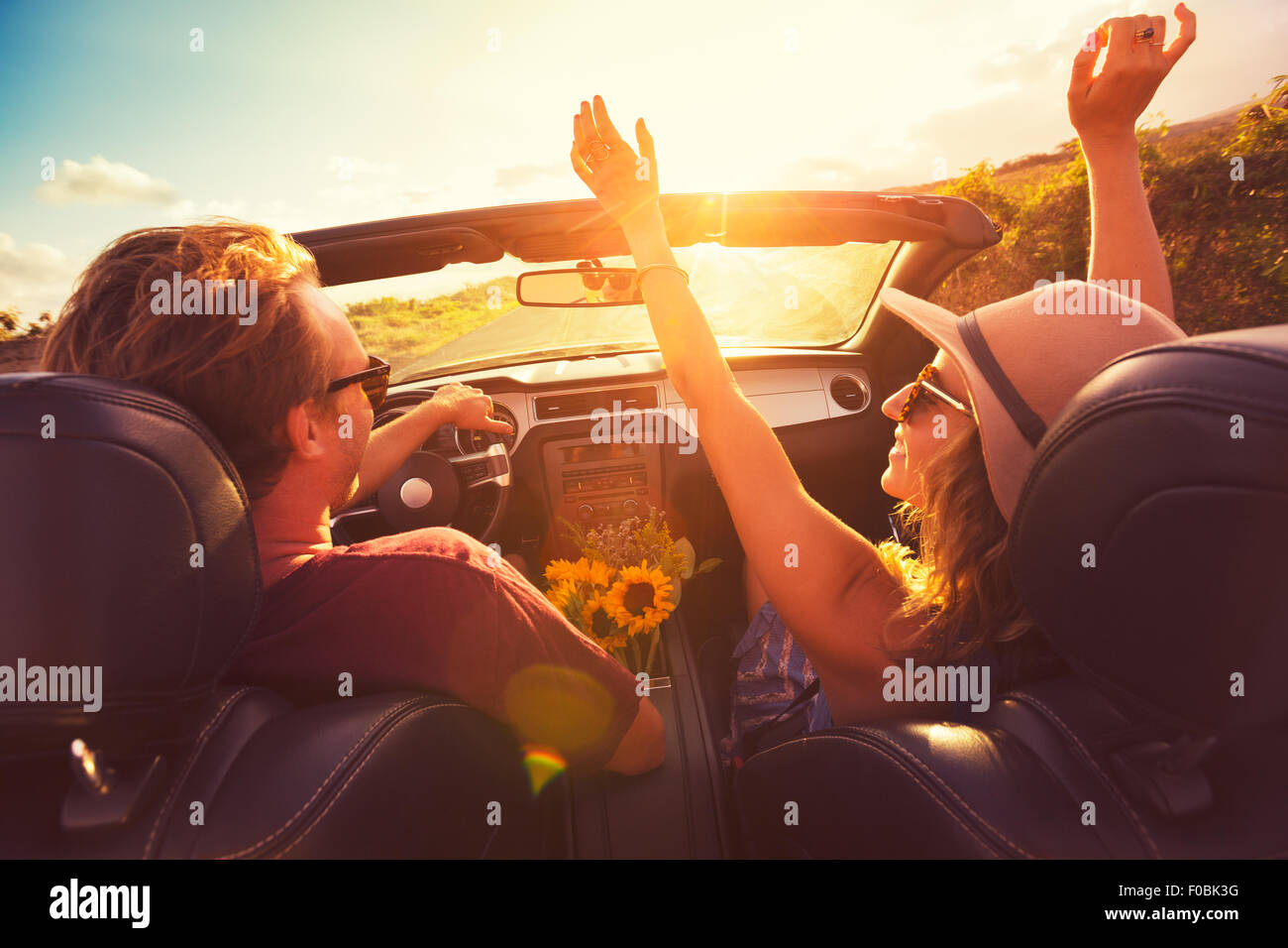 Happy Young Couple Driving Along Country Road in Convertable at Sunset ...