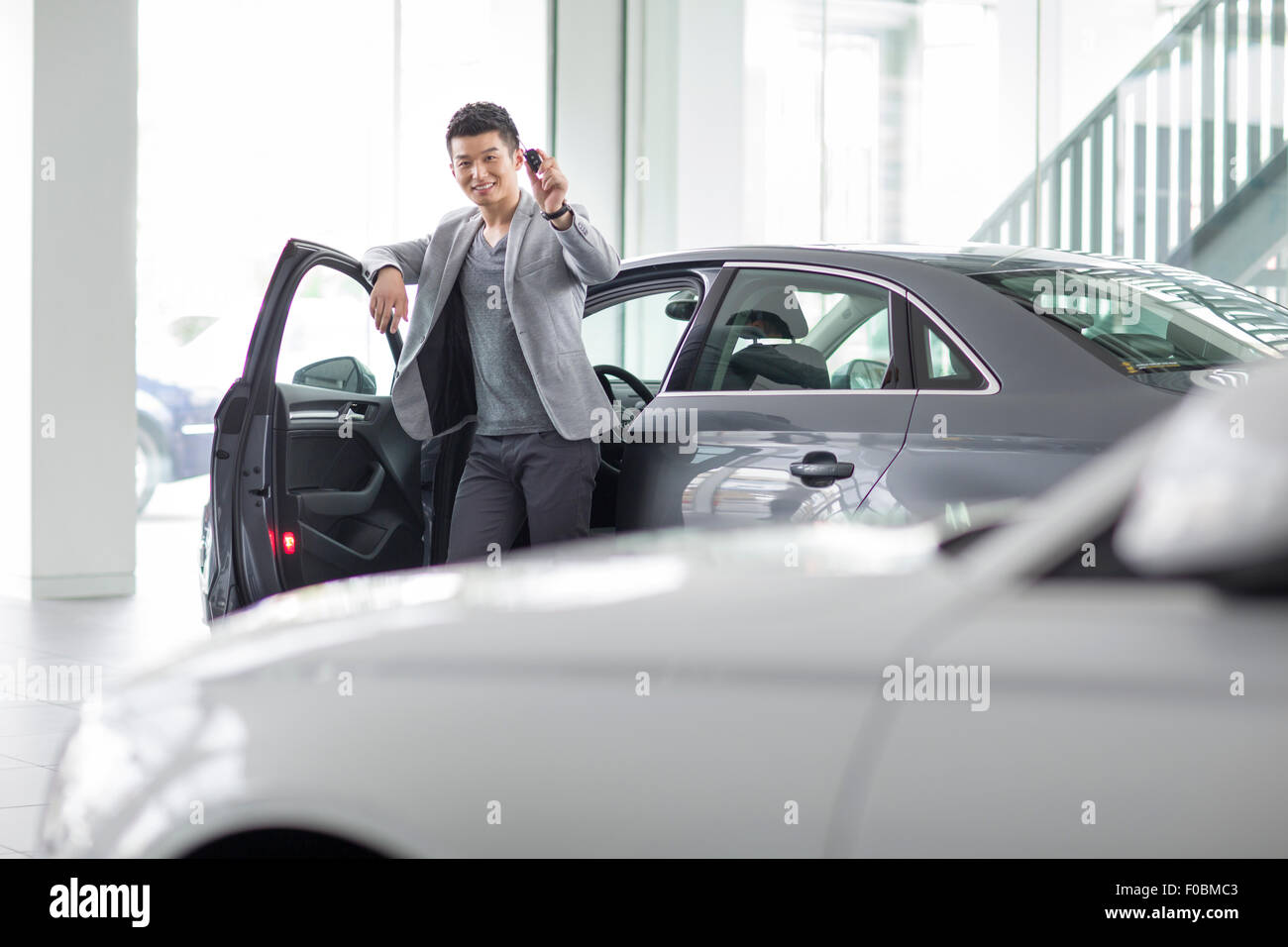 Young man buying car in showroom Stock Photo - Alamy